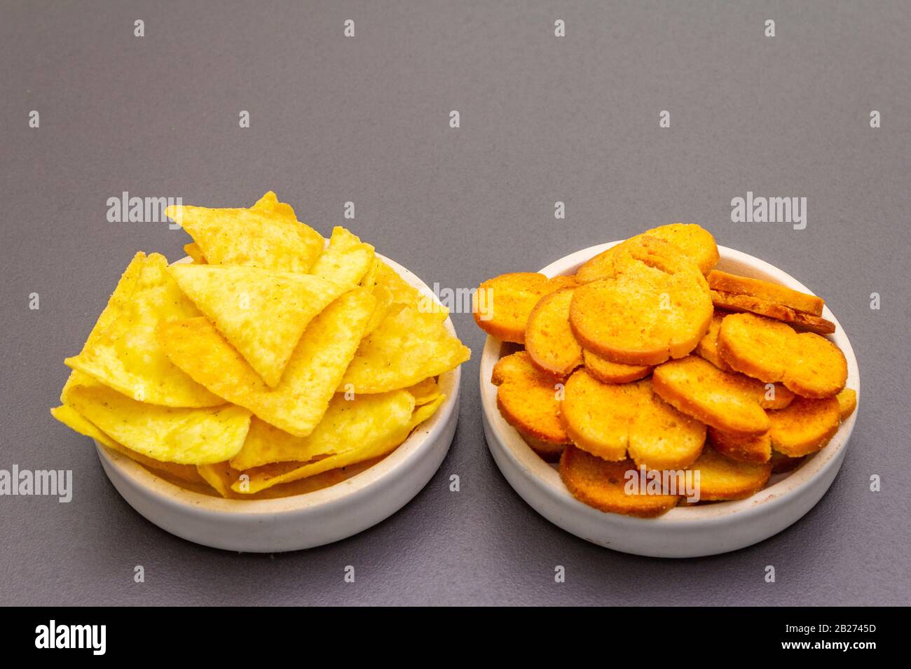 Assorted salty spiced snacks. Nachos, crackers. In ceramic bowls on a ...