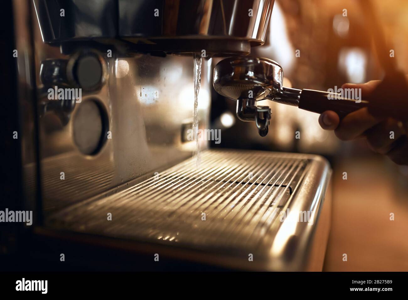 young man holding portofilter brewing coffee at work. close up side ...