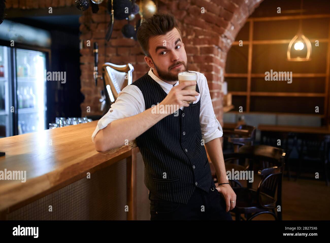 young waiter relaxing after working day, drinking cocktail , close up ...