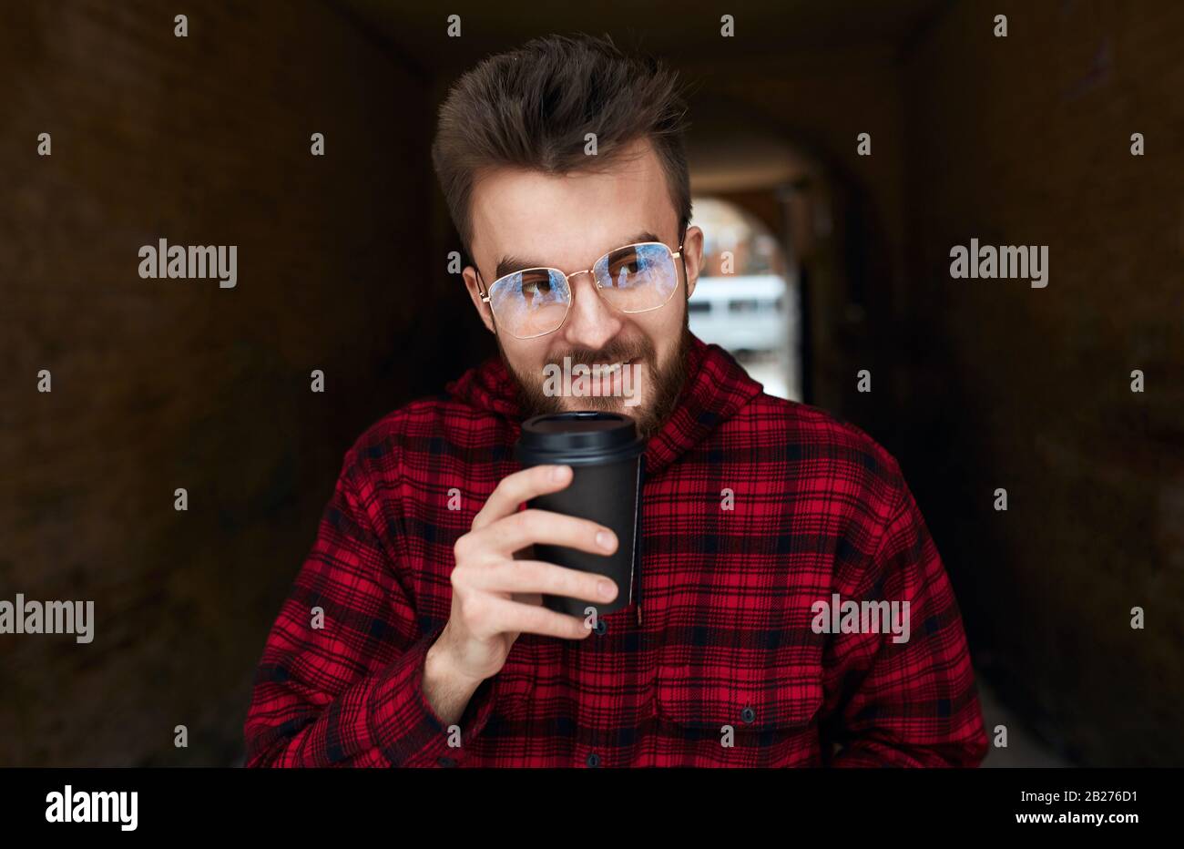cheerful pleasant guy in glasses holding a cup of latte, enjoying ...