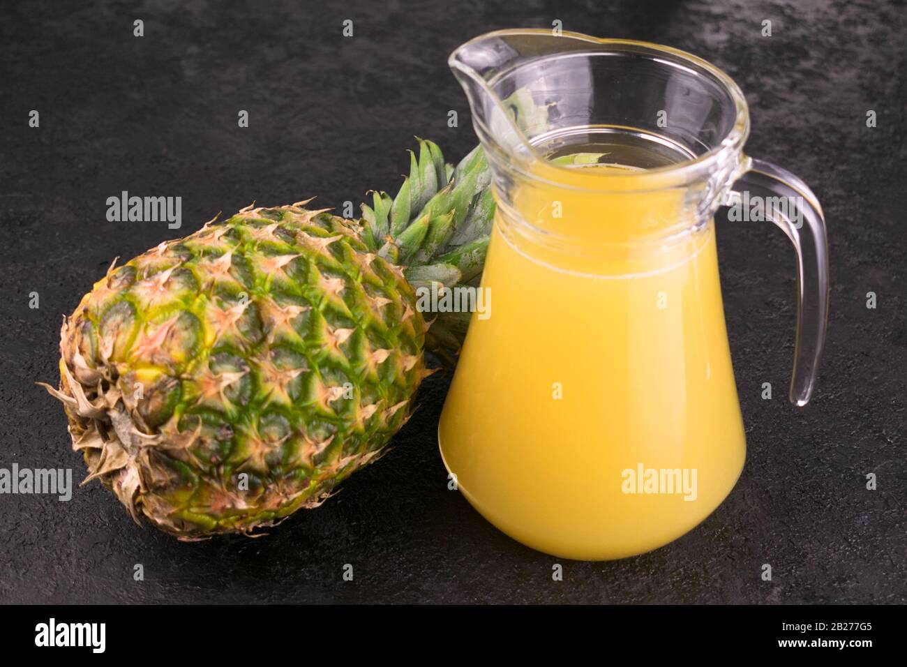 Pineapple and jug with pineapple juice on a black background Stock Photo - Alamy