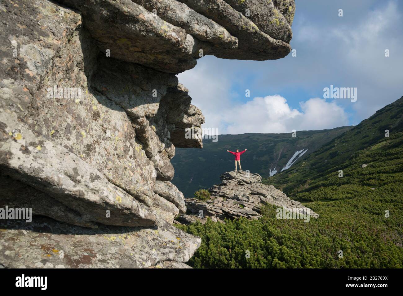 Small human figure in a red jacket among the majestic mountains Stock ...