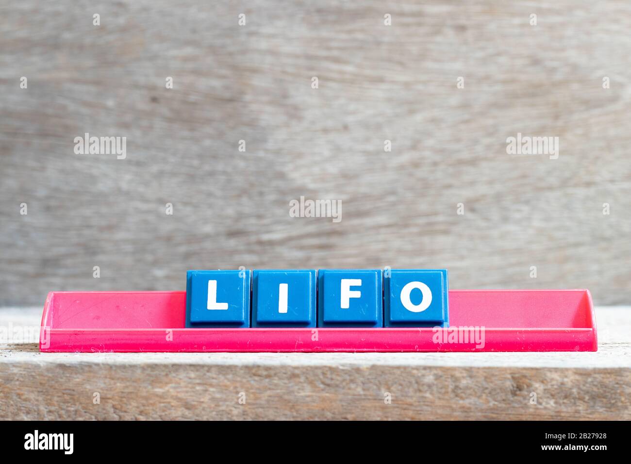 Tile letter on red rack in word LIFO (abbreviation of last in first out) on wood background ...