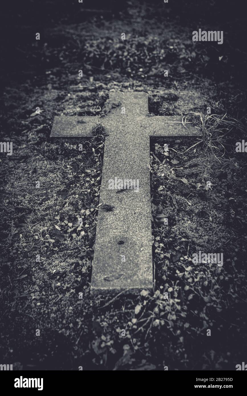 A stone cross in the ground at a graveyard in Sheffield. Shot in Black ...