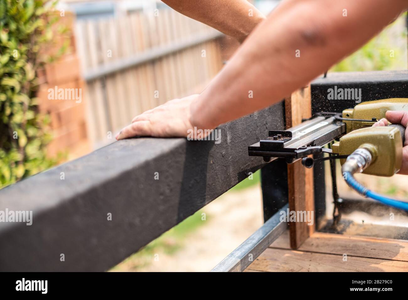 Closeup of a hand man carpenter using air nail gun to complete wood ...