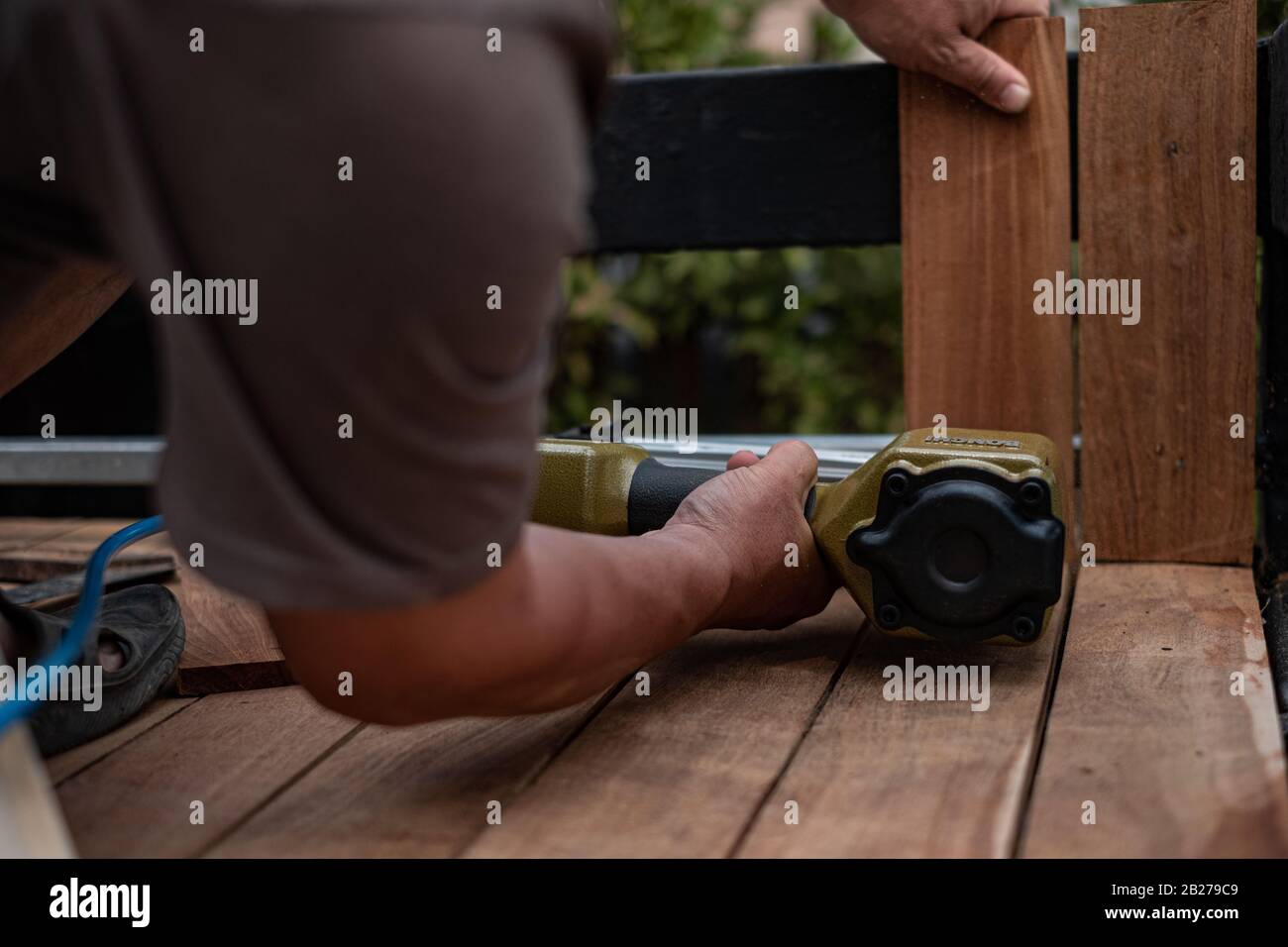 Closeup of a hand man carpenter using air nail gun to complete wood ...
