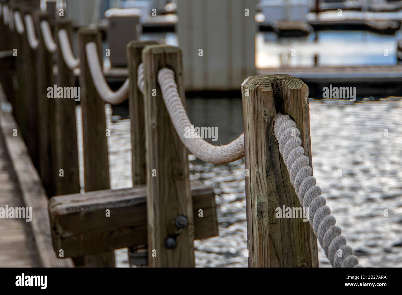 The rope barrier supported by wooden beams near the water of a harbor ...