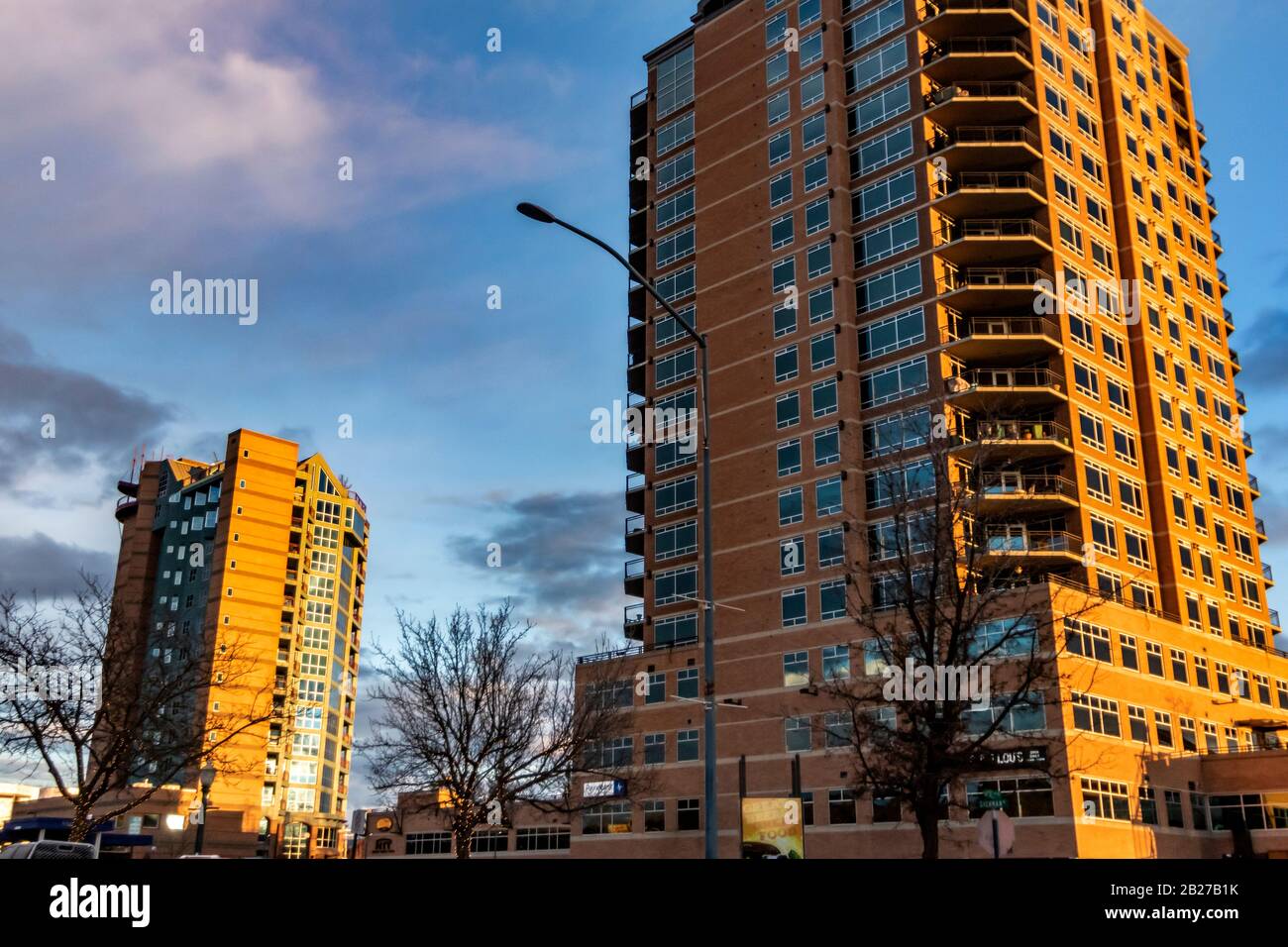 Tall side lit red brick high rise building with a smaller building on ...