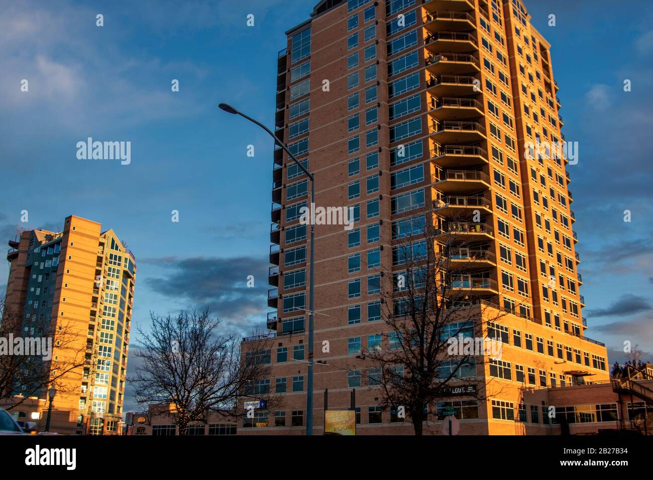 Tall side lit red brick high rise building with a smaller building on ...