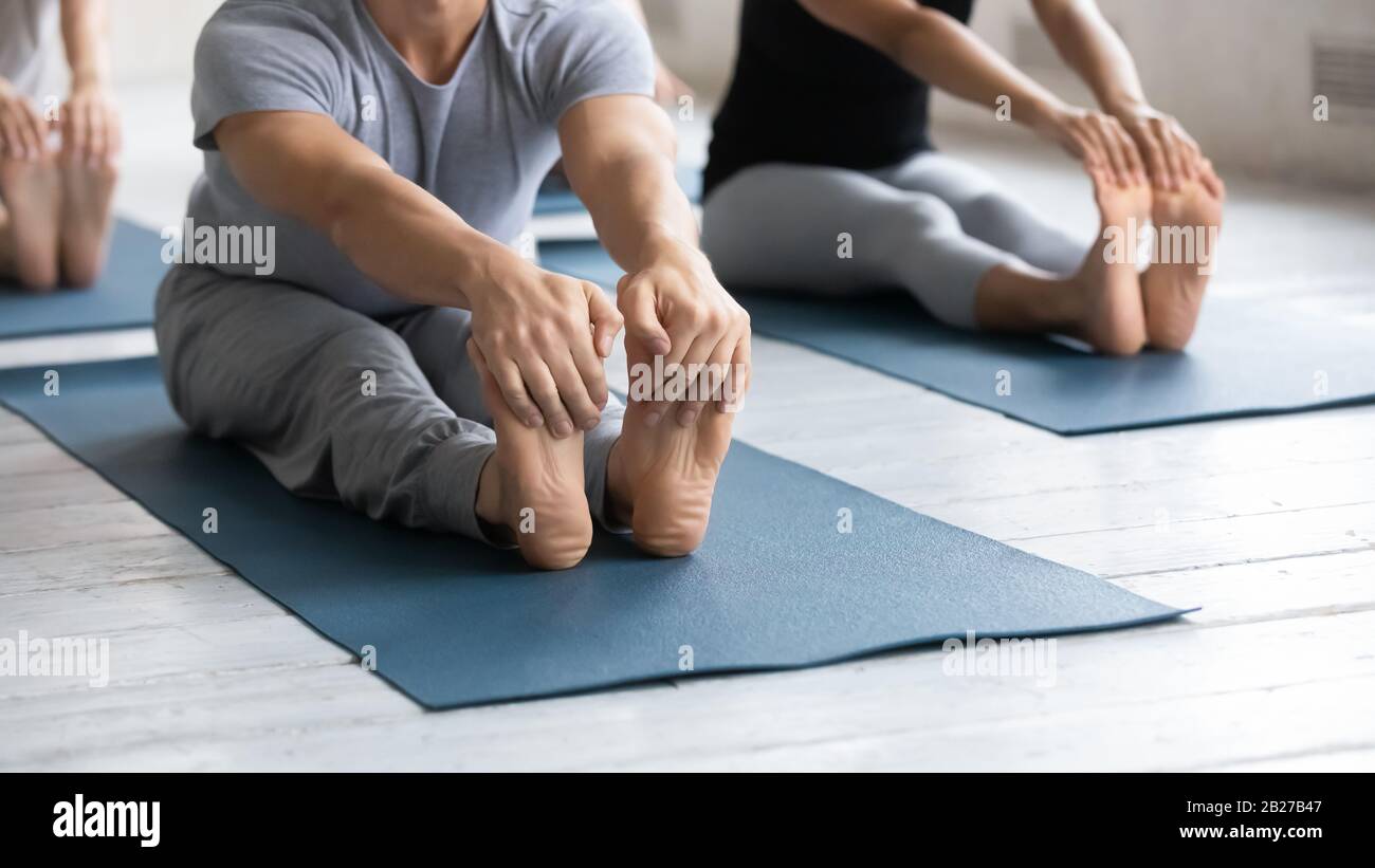 Sportive girls and guys performing Seated Forward Bend exercise Stock ...