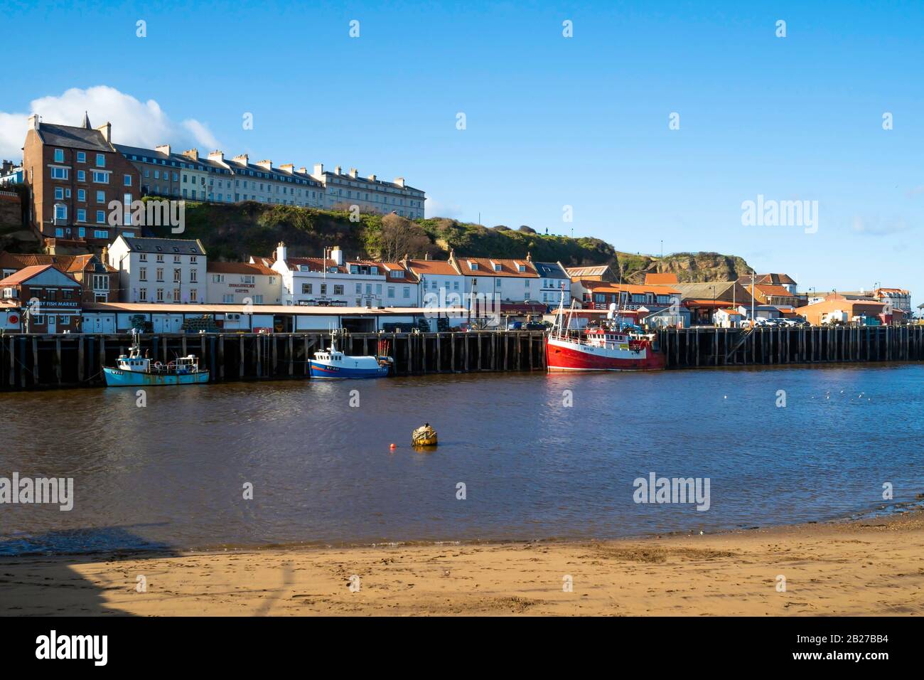 Blue and red fishing boats tied up at the fish quay in Whitby harbour ...