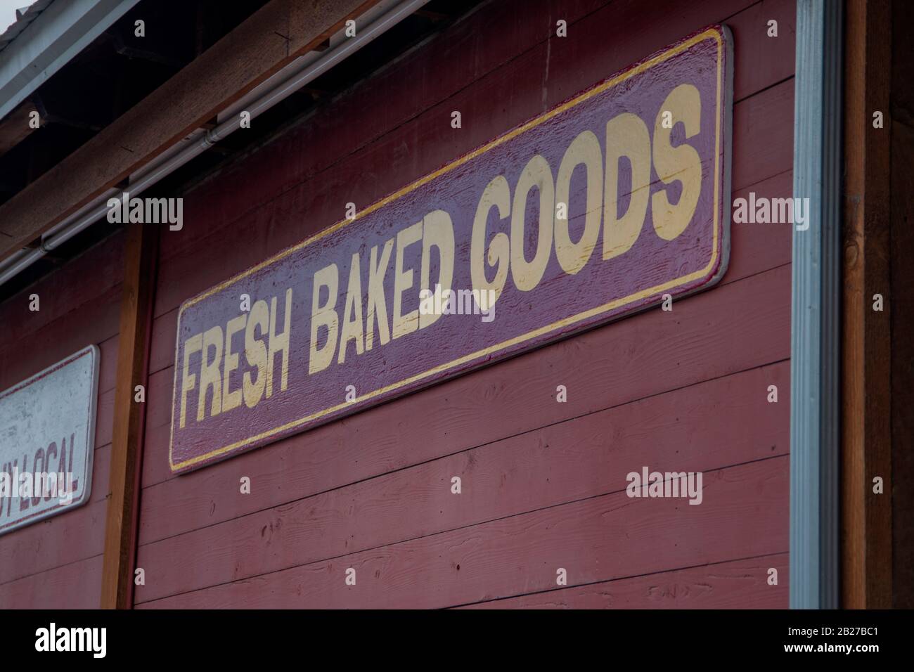 Side View of Fresh Baked Goods Sign hanging on a red exterior wall ...