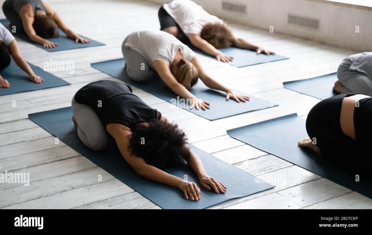 Group of people lying on mats performing Child Pose asana Stock Photo ...