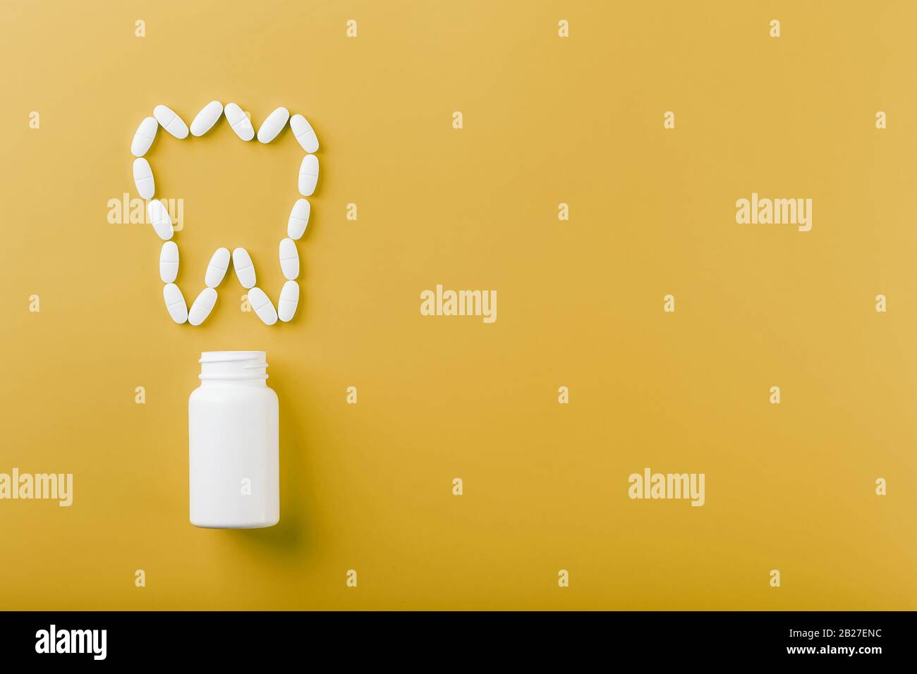 Calcium vitamin in the form of a tooth spilled out of a white jar on a ...