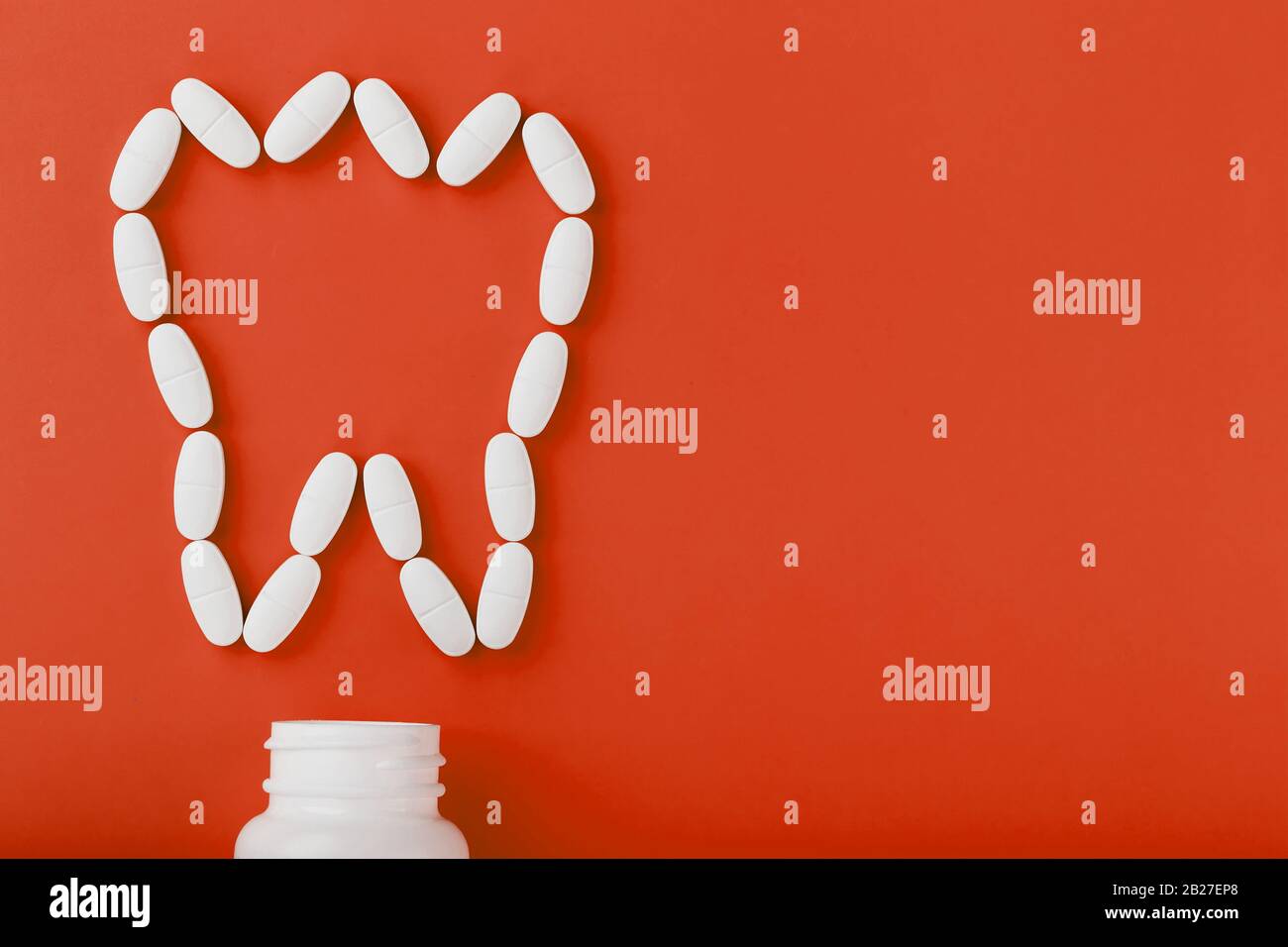 Calcium vitamin in the form of a tooth spilled out of a white jar on a ...