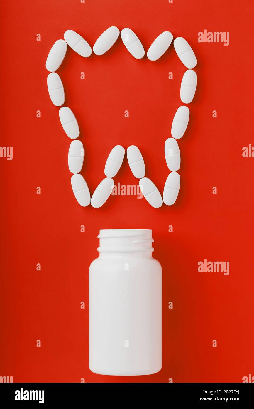 Calcium vitamin in the form of a tooth spilled out of a white jar on a ...