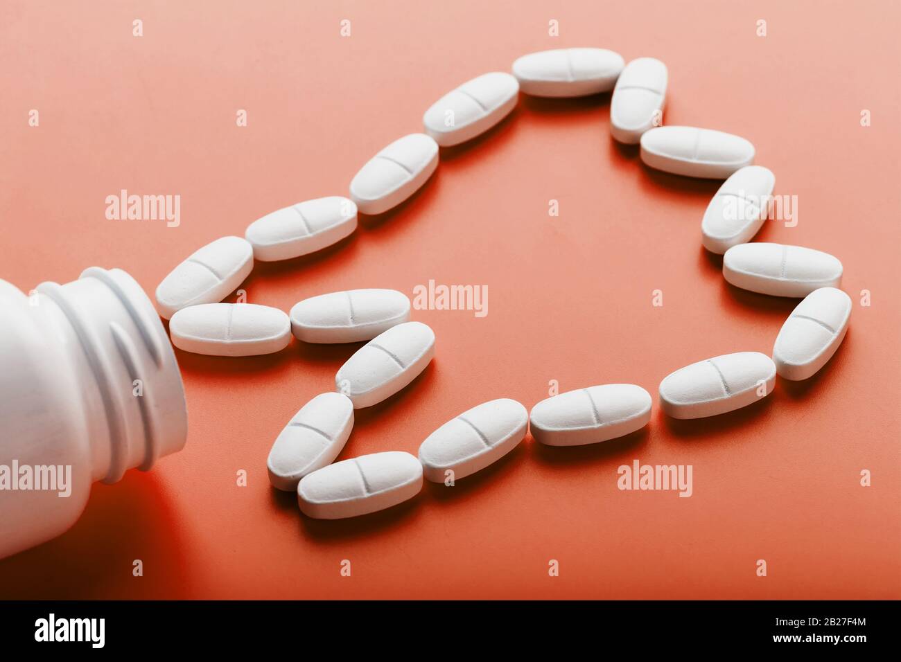 Calcium vitamin in the form of a tooth spilled out of a white jar on a ...