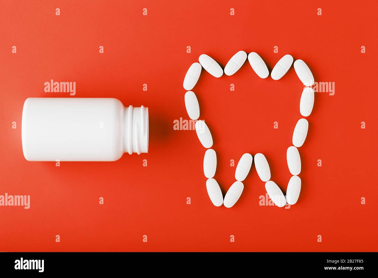 Calcium vitamin in the form of a tooth spilled out of a white jar on a ...