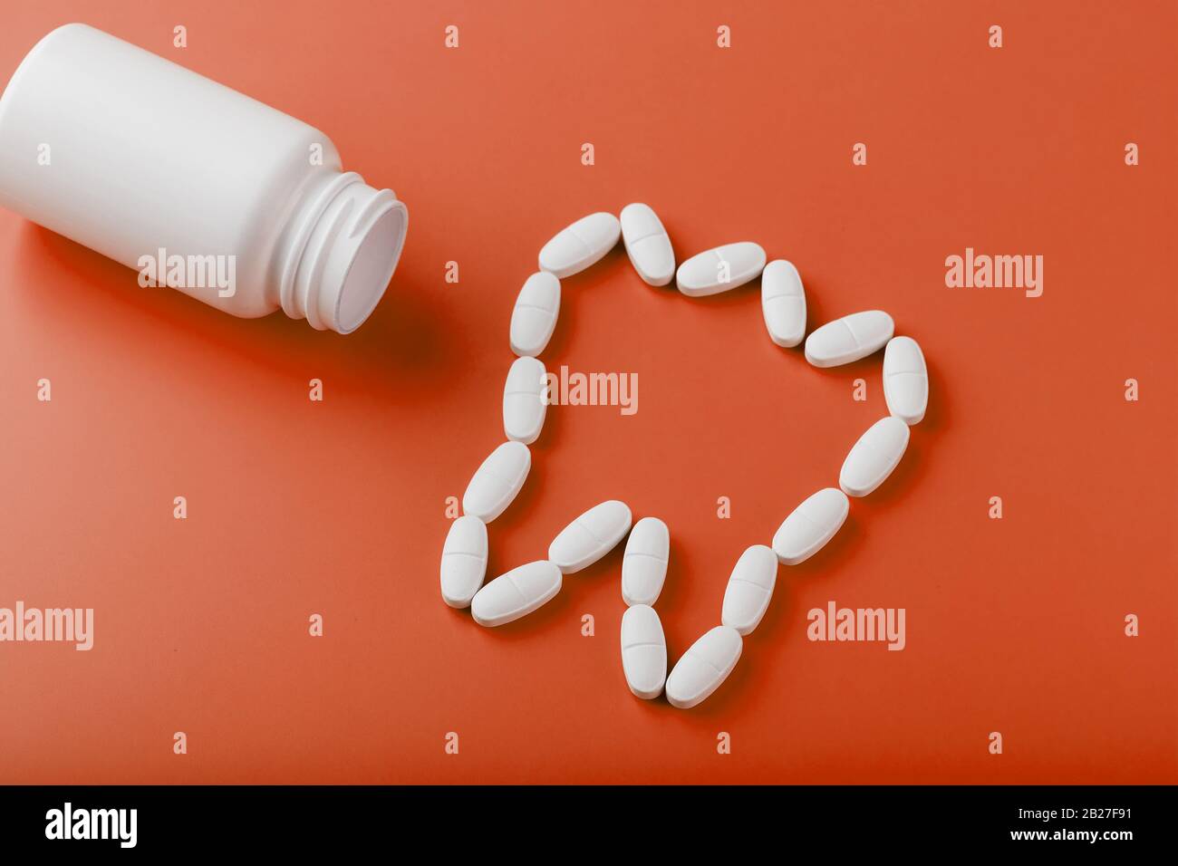 Calcium vitamin in the form of a tooth spilled out of a white jar on a ...