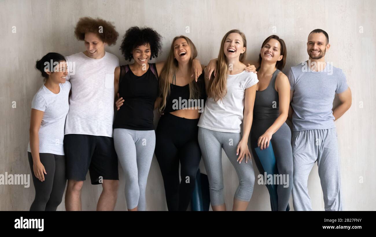 Seven multiethnic people embracing standing posing on studio wall ...