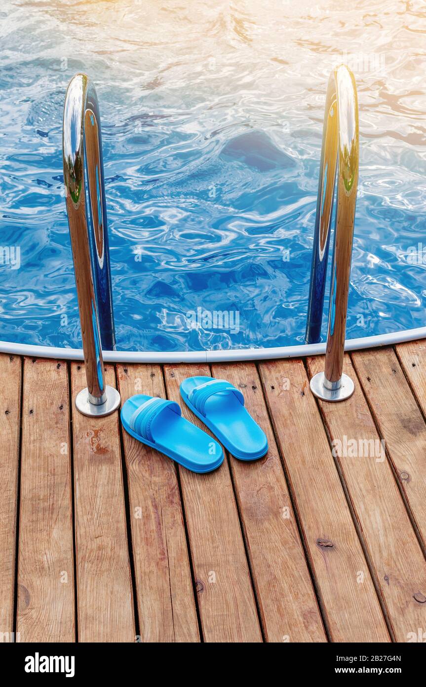 Slippers by the pool with a staircase and a wooden terrace in the hotel ...