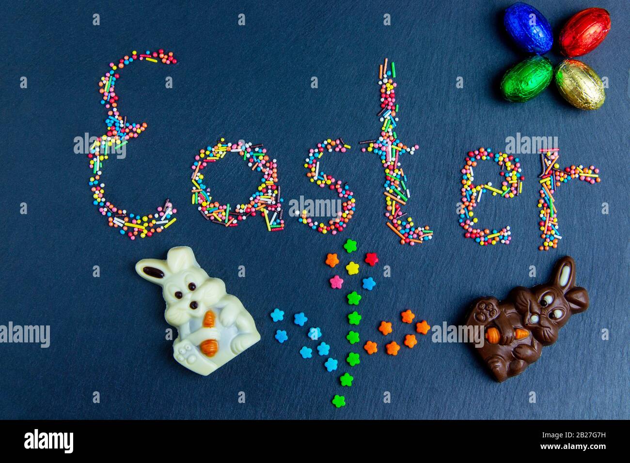 Multicolored candies are laid out in the form of Easter and flower on a ...