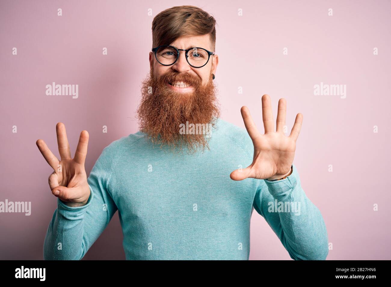 Handsome Irish redhead man with beard wearing glasses over pink ...