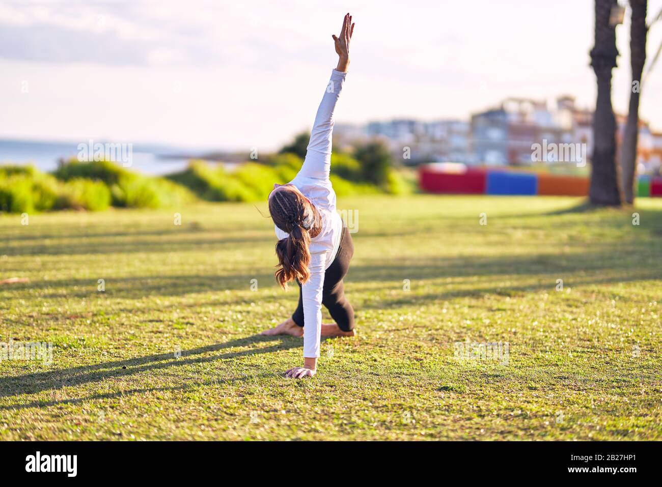 Young beautiful sportwoman practicing yoga. Coach teaching side plank ...