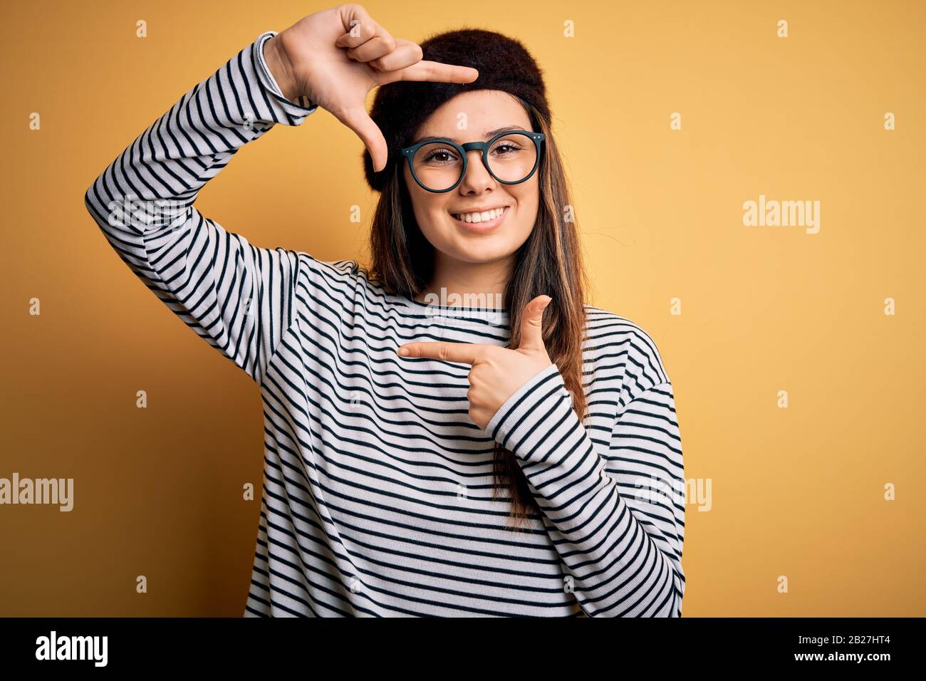 Young beautiful brunette woman wearing french beret and glasses over ...