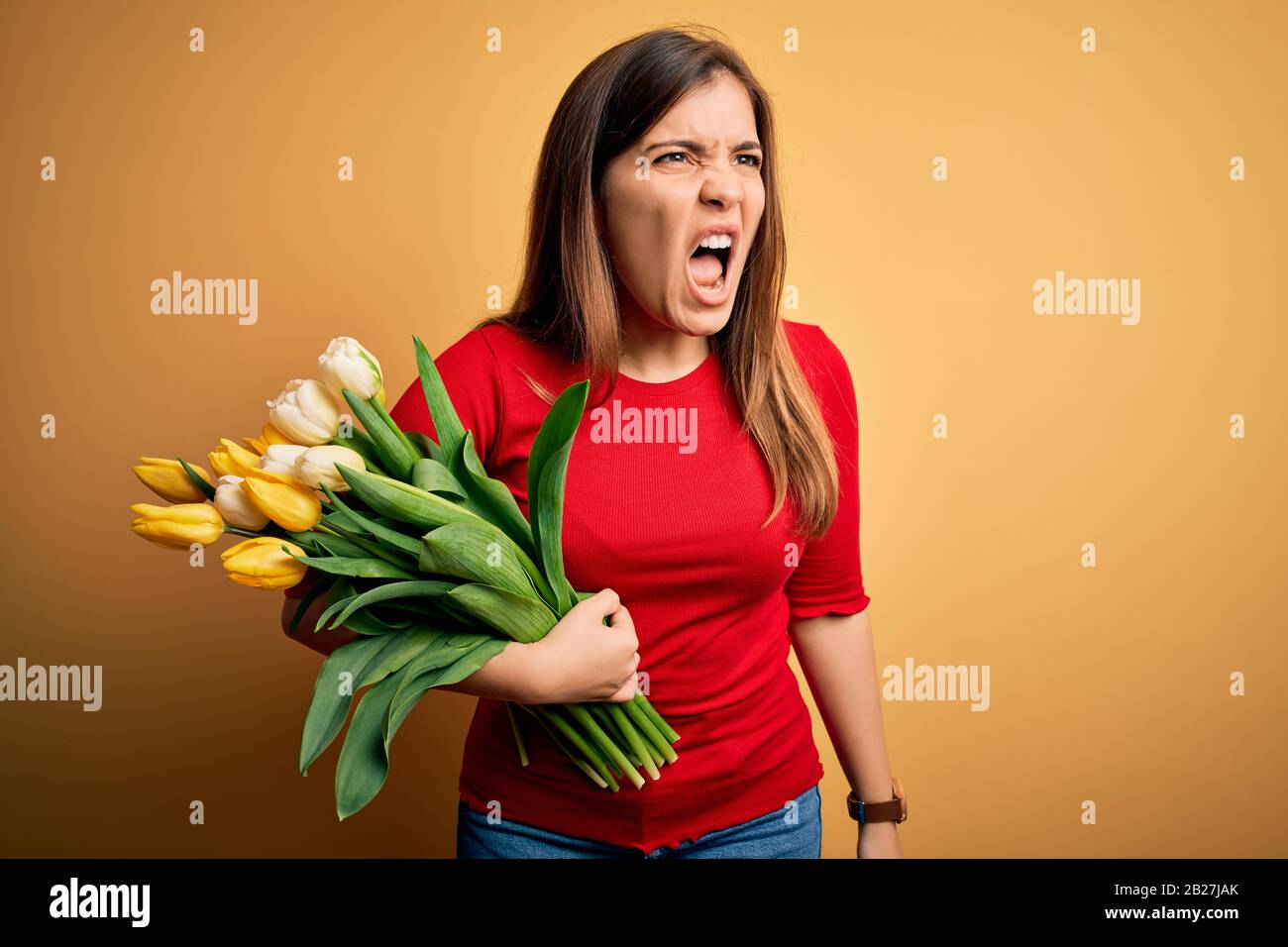 Young blonde woman holding romantic bouquet of tulips flowers over ...