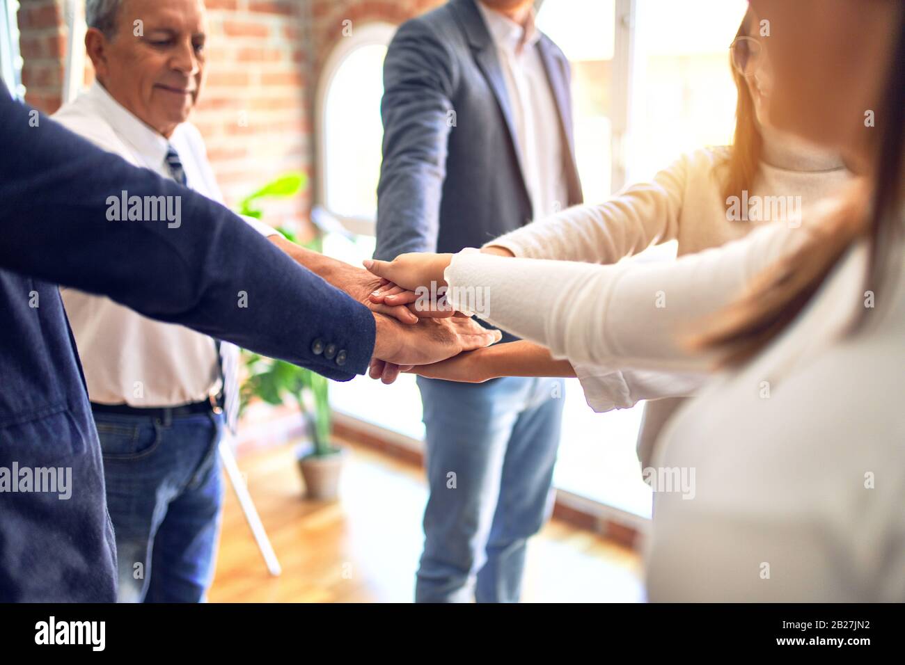 Group of business workers standing with hands together at the office ...