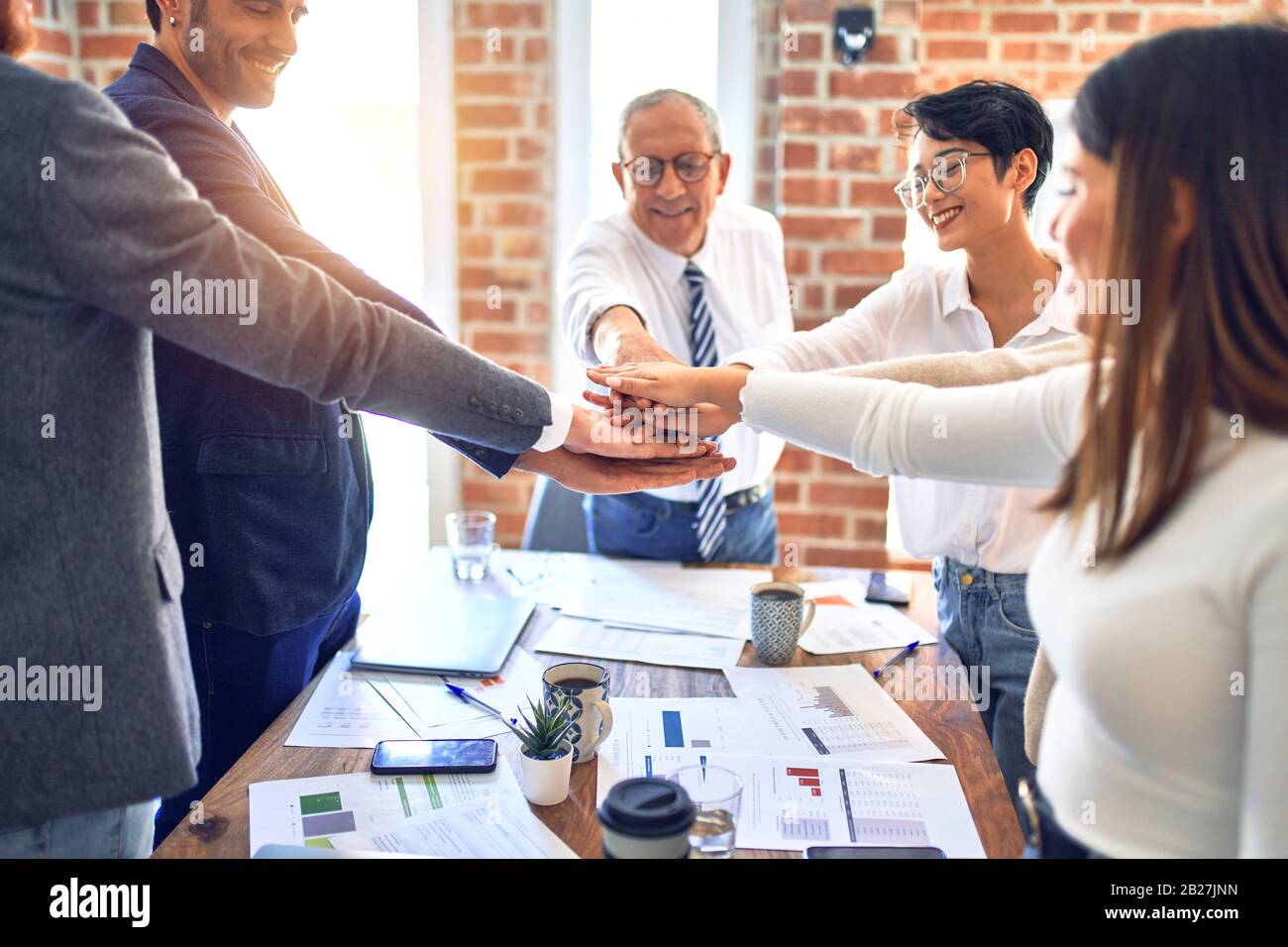Group of business workers standing with hands together at the office ...