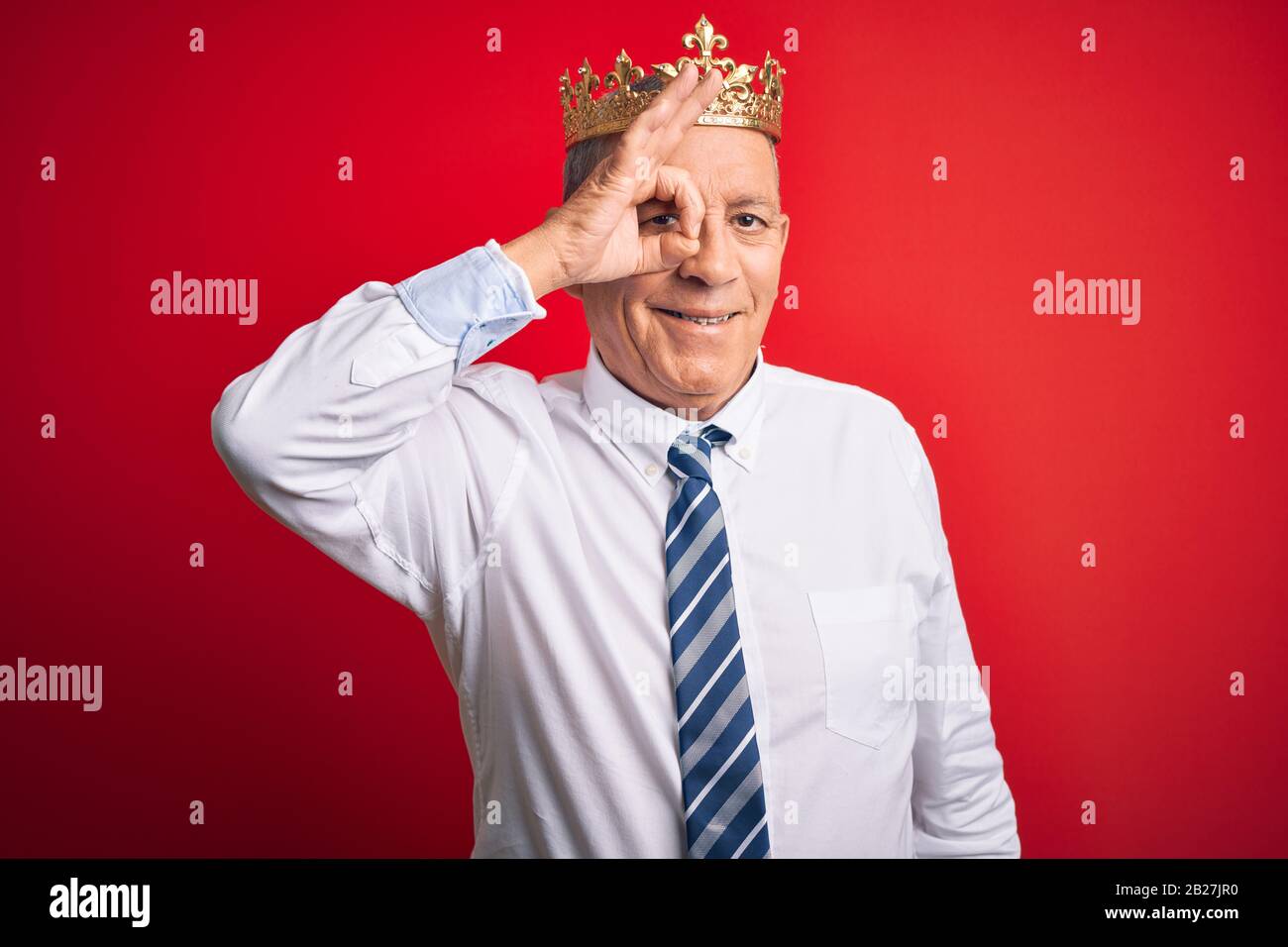 Senior handsome businessman wearing king crown standing over isolated ...