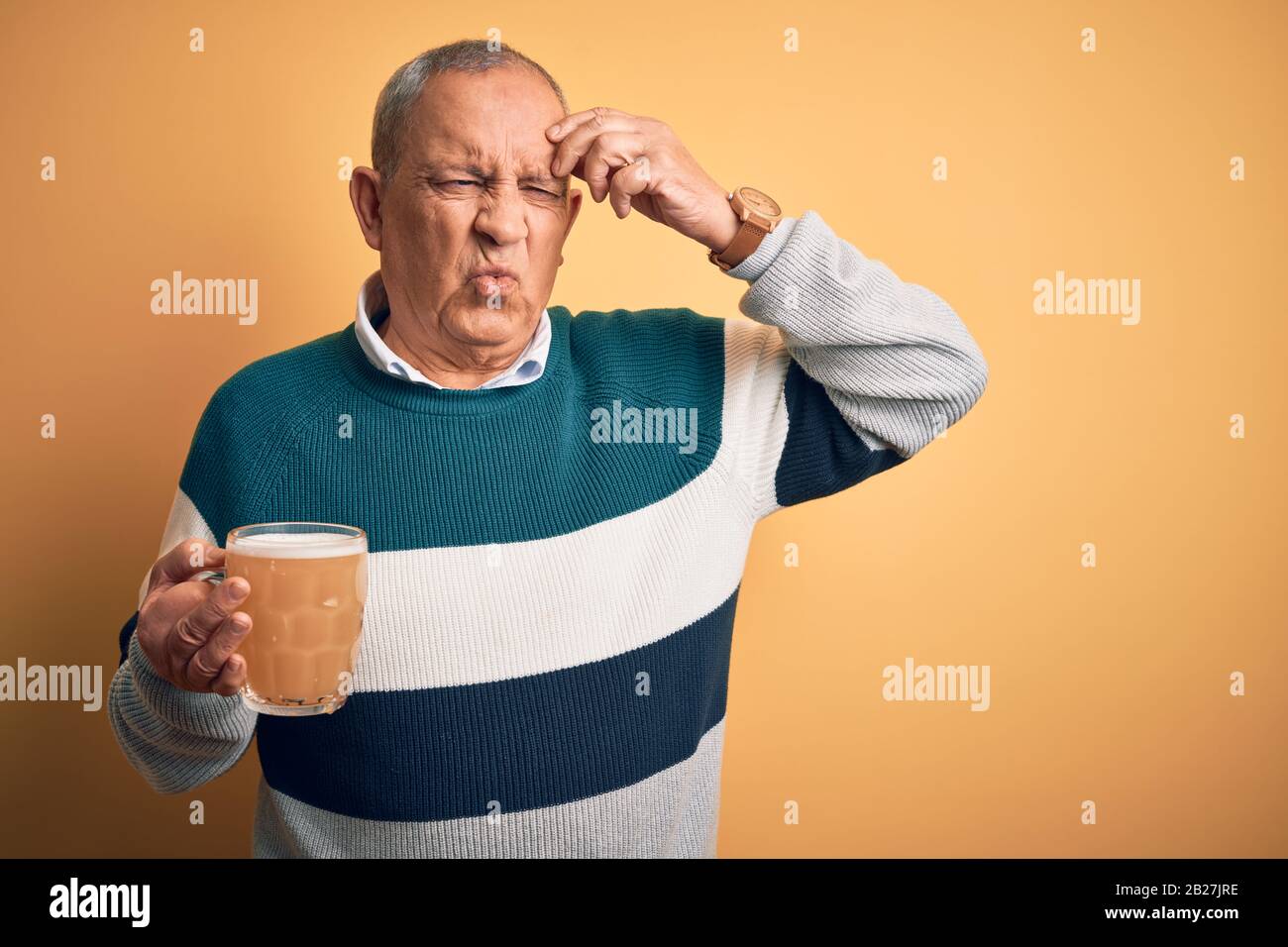 Senior handsome man drinking jar of beer standing over isolated yellow ...