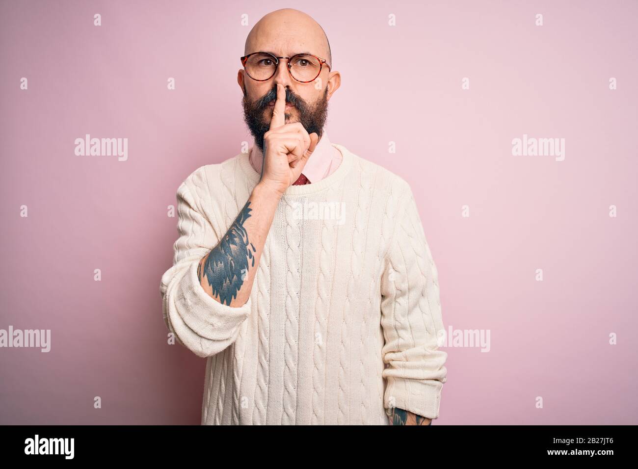 Handsome bald man with beard and tattoo wearing glasses and sweater ...