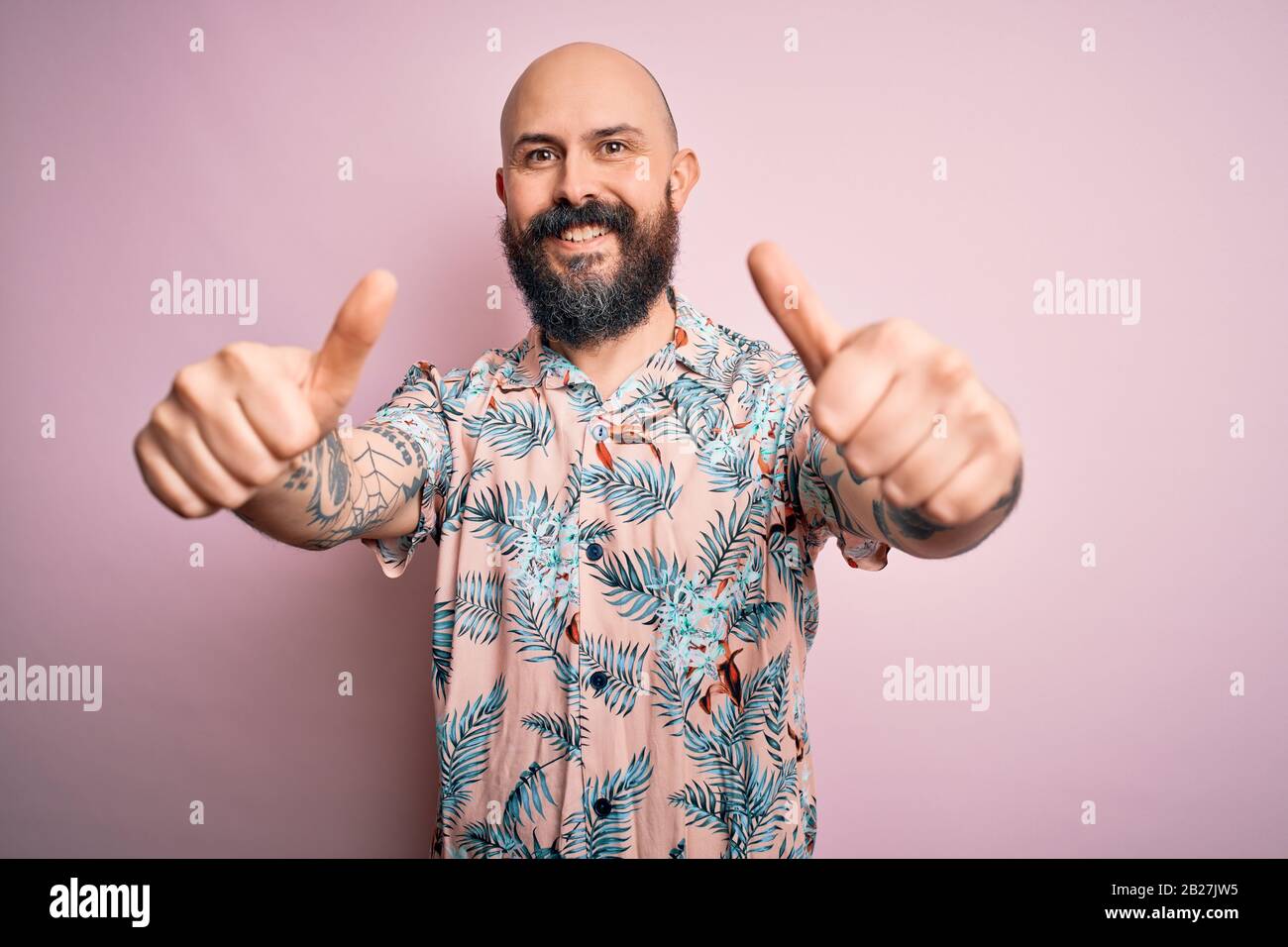 Handsome bald man with beard and tattoo wearing casual floral shirt ...