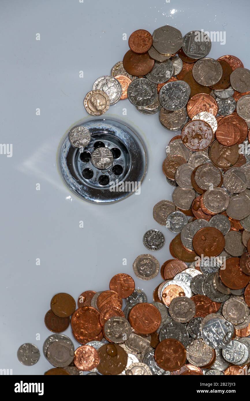 Overhead shot of coins around a plug hole in a bath as if the are ...