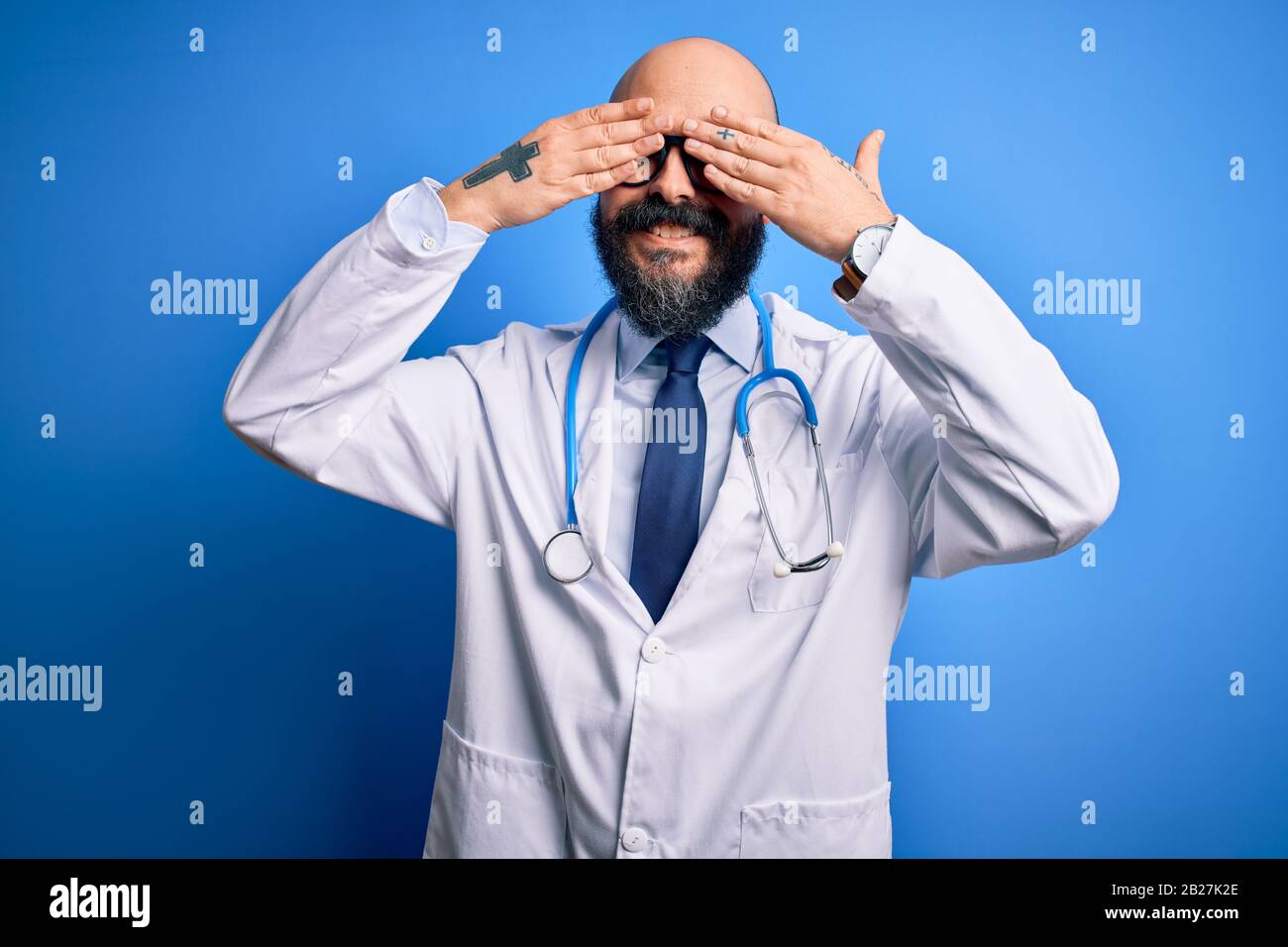 Handsome bald doctor man with beard wearing glasses and stethoscope ...