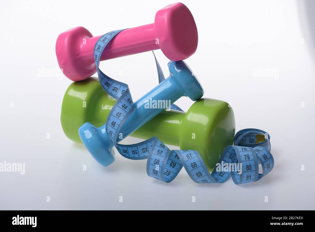 Dumbbells near blue rolled ruler on white background. Health regime and ...
