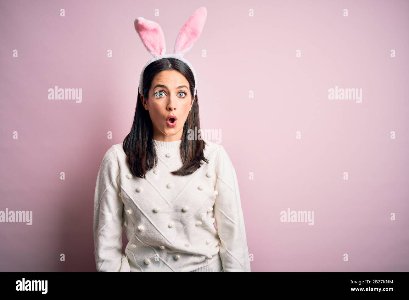 Young caucasian woman wearing cute easter rabbit ears over pink ...