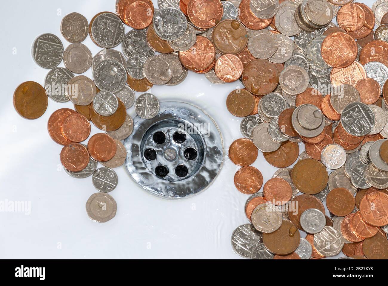Overhead shot of coins around a plug hole in a bath as if the are ...