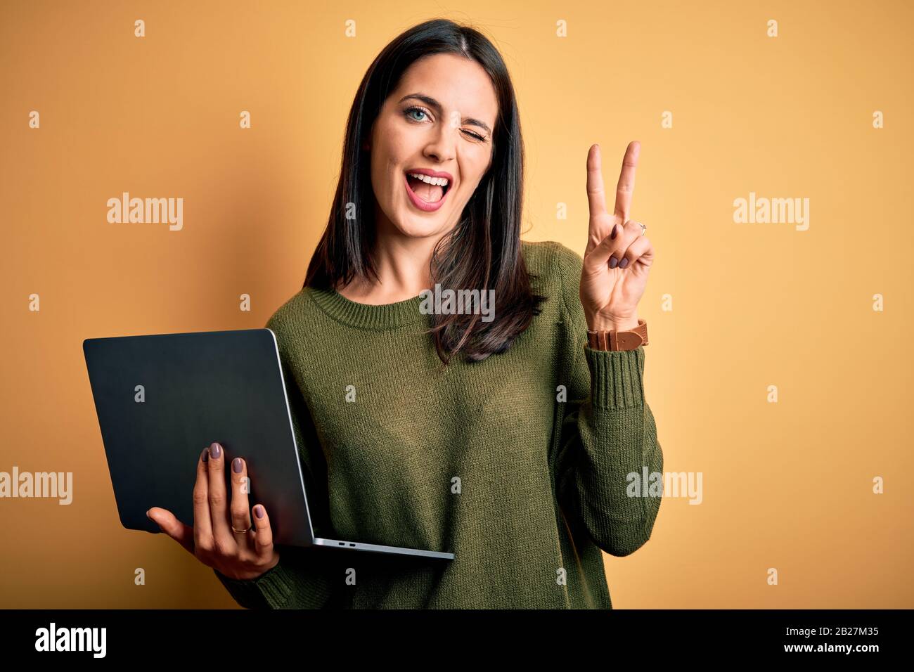 Young brunette woman with blue eyes working using computer laptop over ...