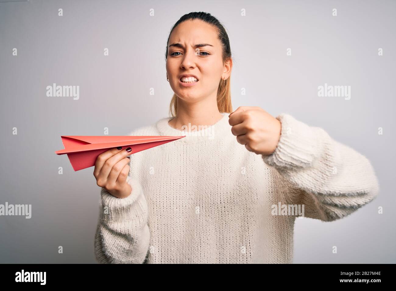 Beautiful blonde woman with blue eyes holding red paper airplane over ...