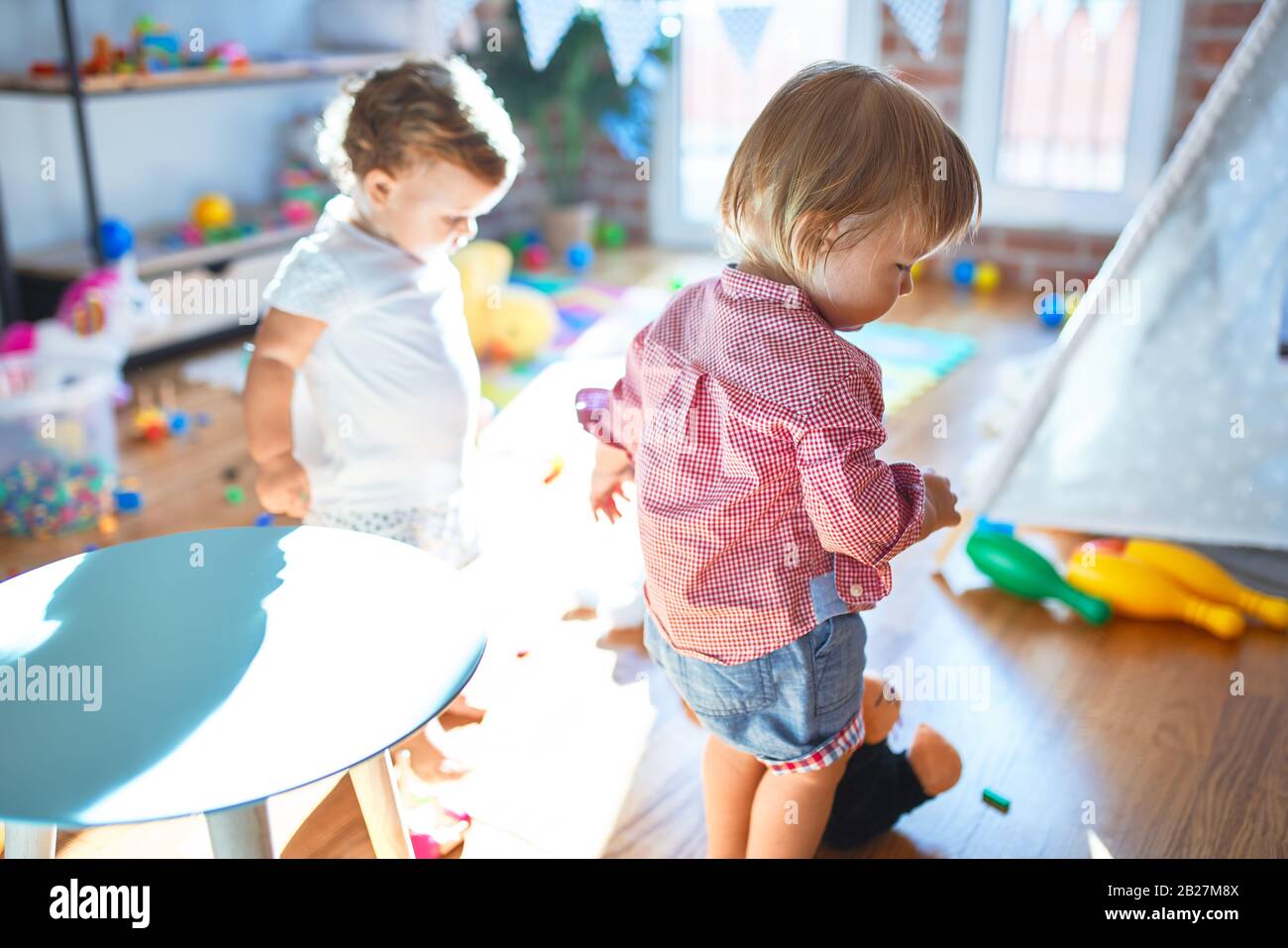 Adorable toddlers playing around lots of toys at kindergarten Stock ...