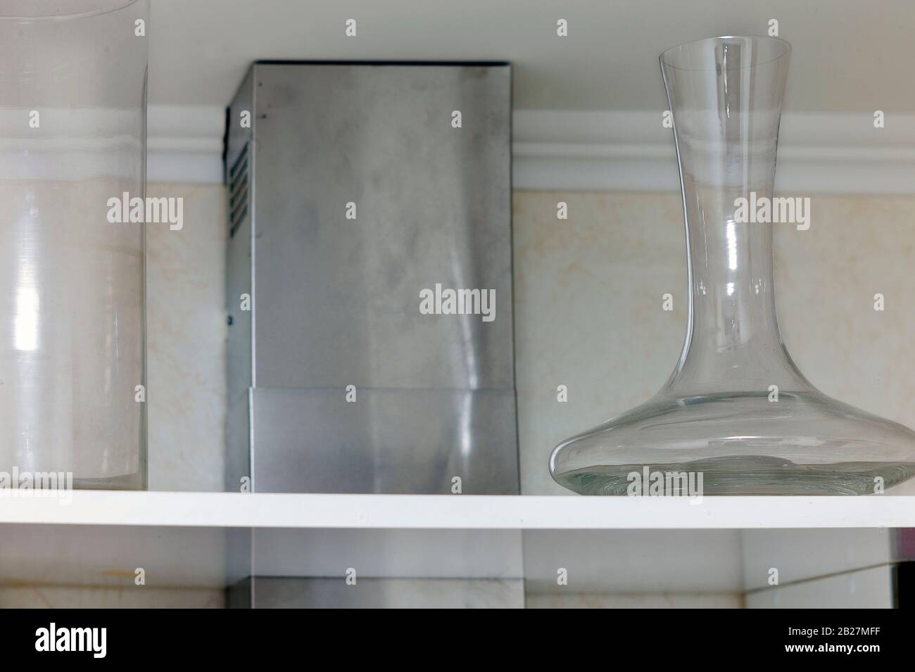 Empty decanter and a glass vase on the kitchen shelf, indoor closeup ...