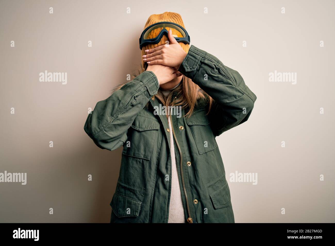 Young brunette skier woman wearing snow clothes and ski goggles over ...