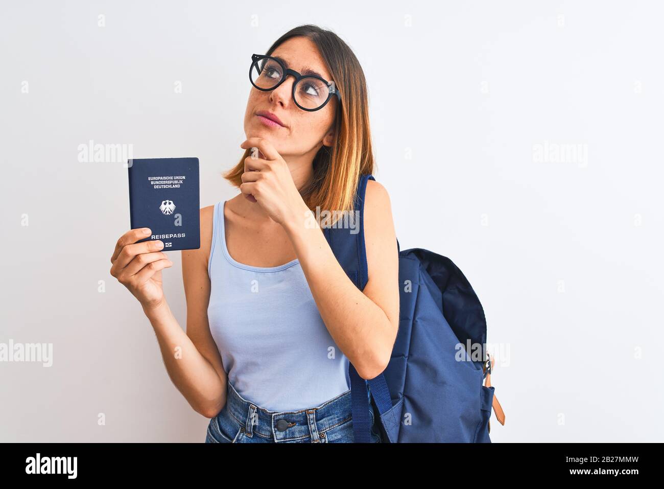 Beautiful redhead student woman wearing backpack and holding passport ...