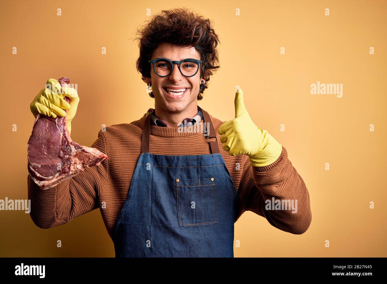 Young handsome butcher man holding meet steak standing over isolated ...