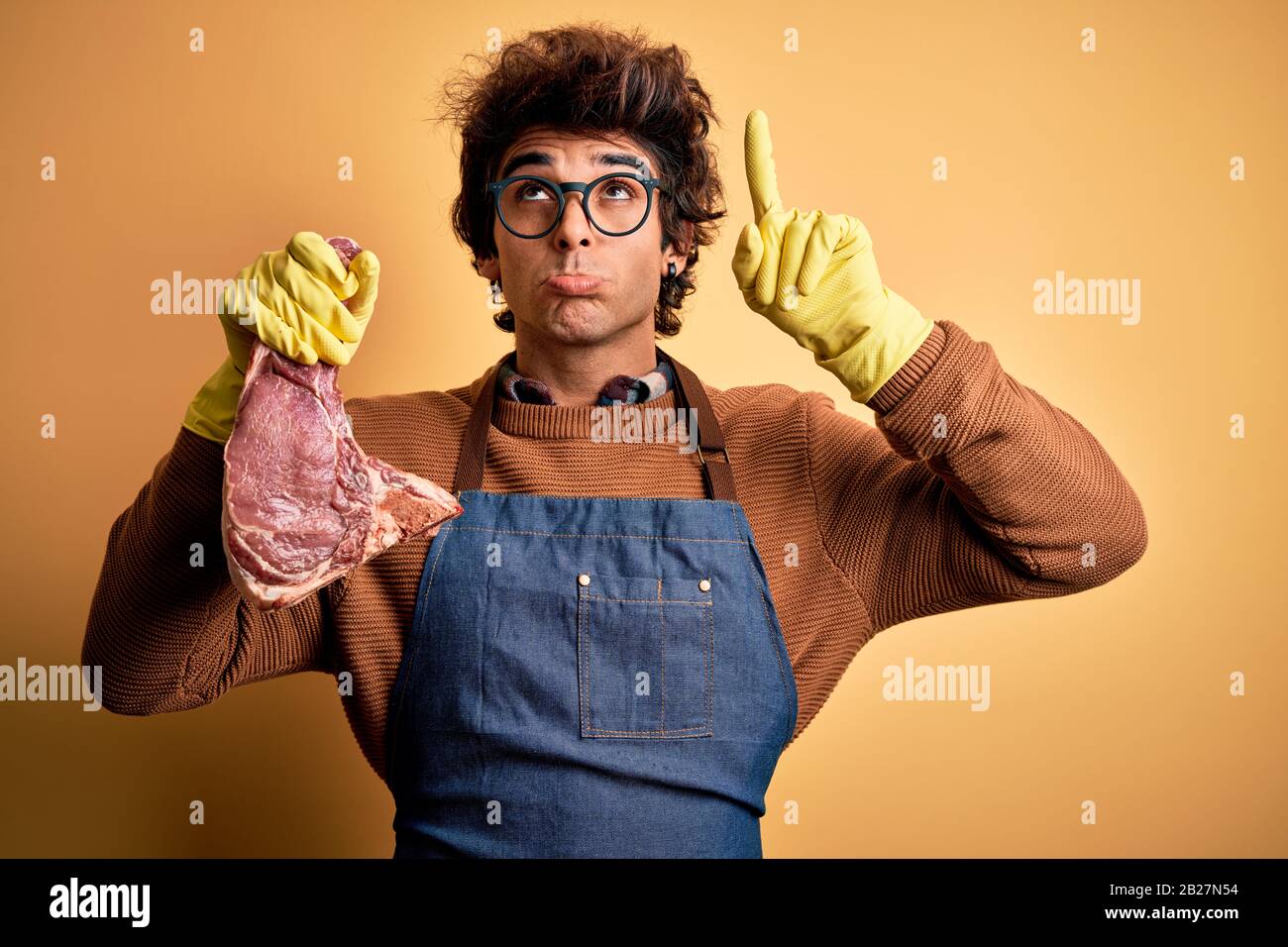 Young handsome butcher man holding meet steak standing over isolated ...