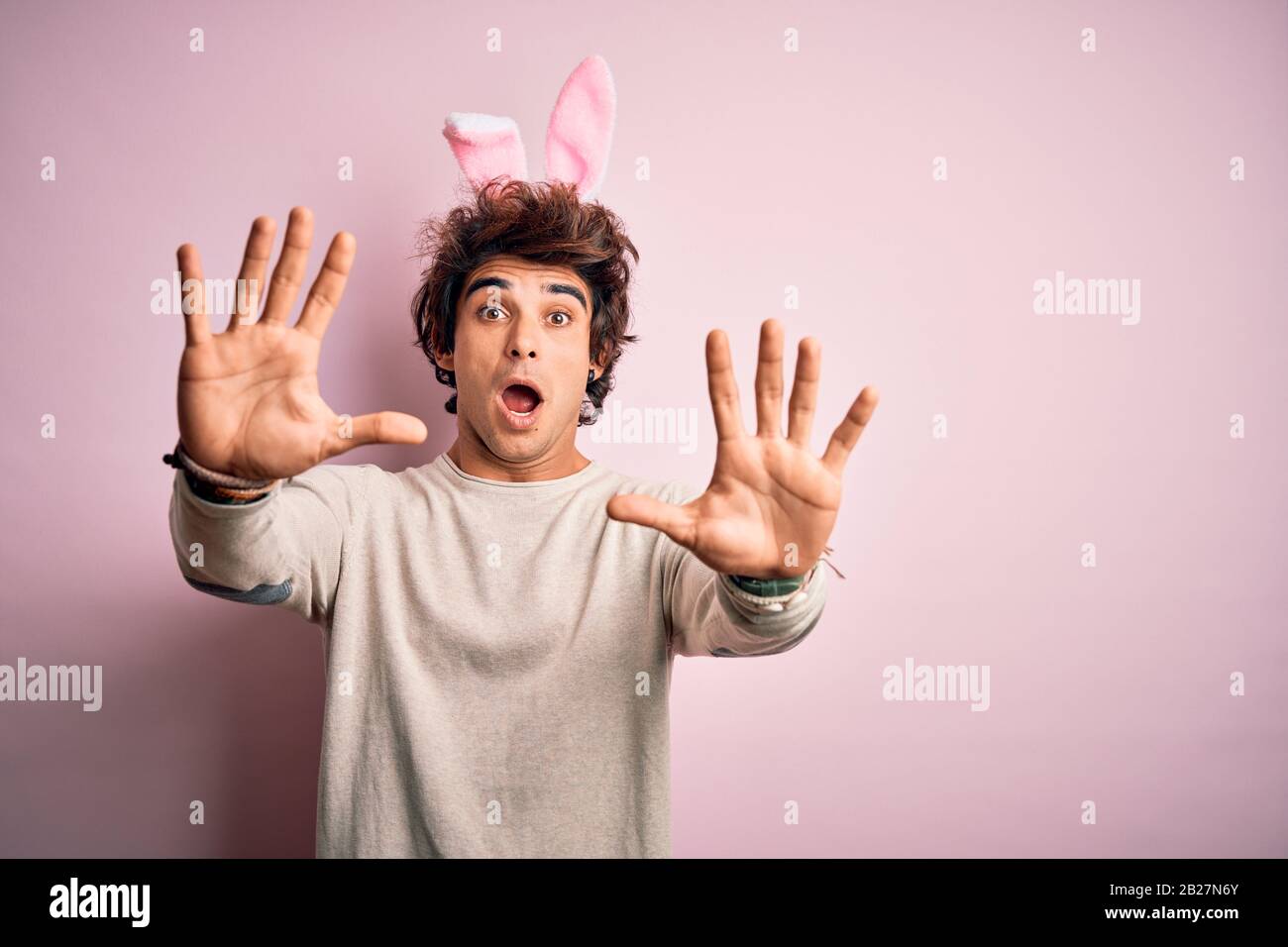 Young handsome man holding easter rabbit ears standing over isolated ...